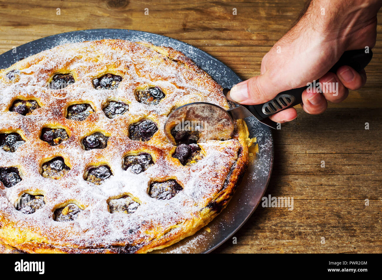 Male hand cutting sweet pie with a roller cutter Stock Photo - Alamy