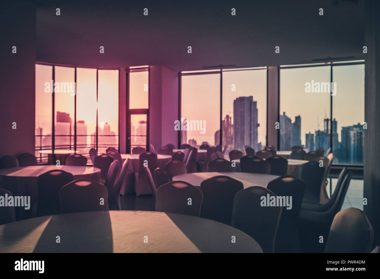 empty dinner table in room with view over modern skyline during sunset ...