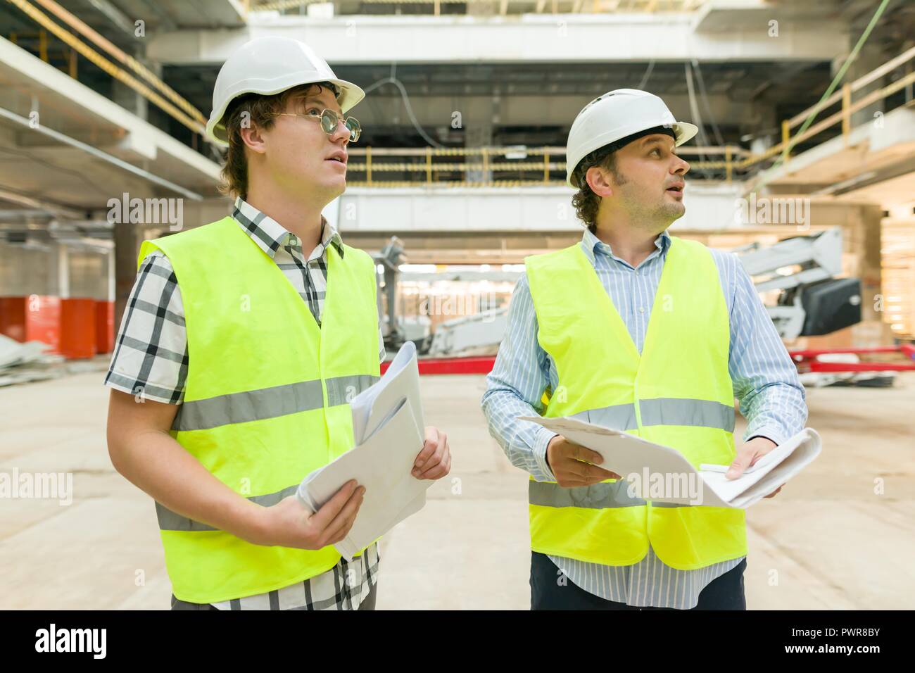 Male construction worker and engineer at the construction site ...