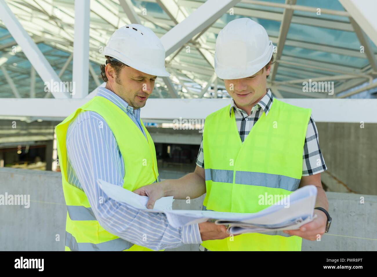 Male construction worker and engineer at the construction site ...