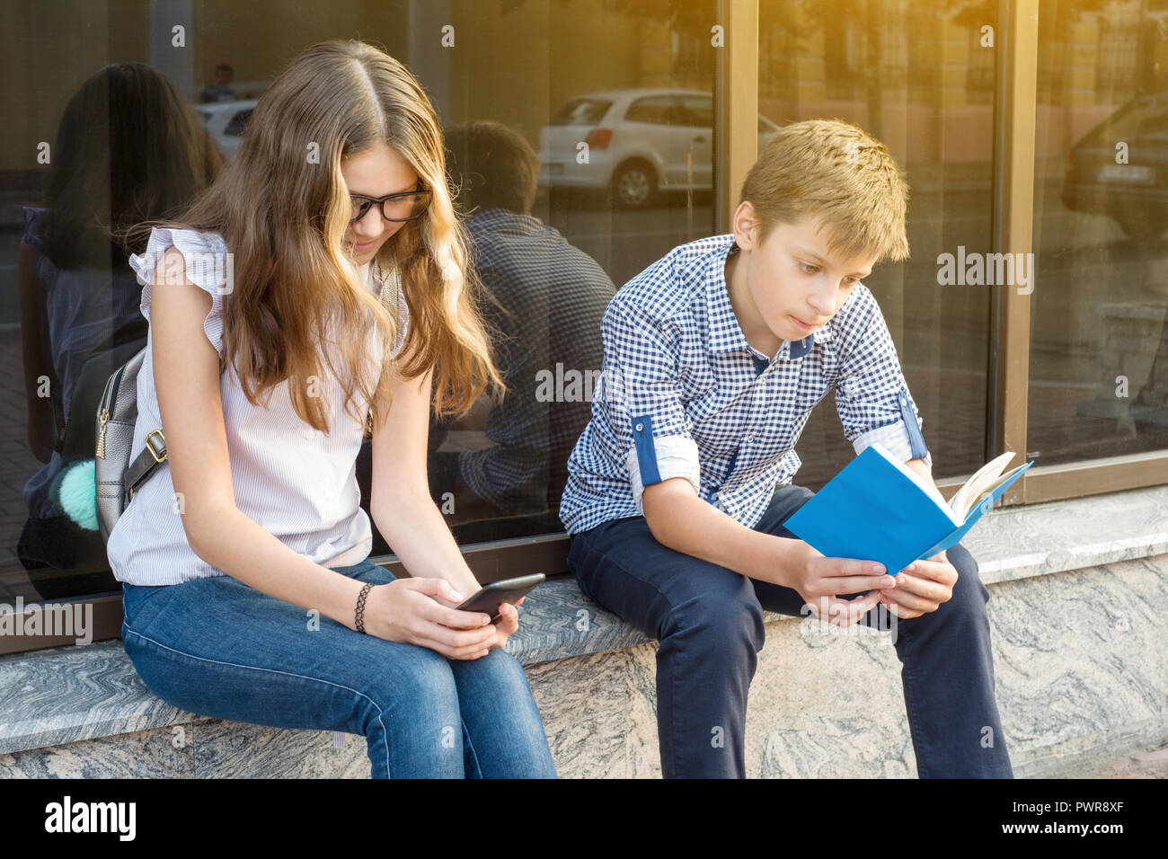 Boy and girl with mobile and textbook hi-res stock photography and ...