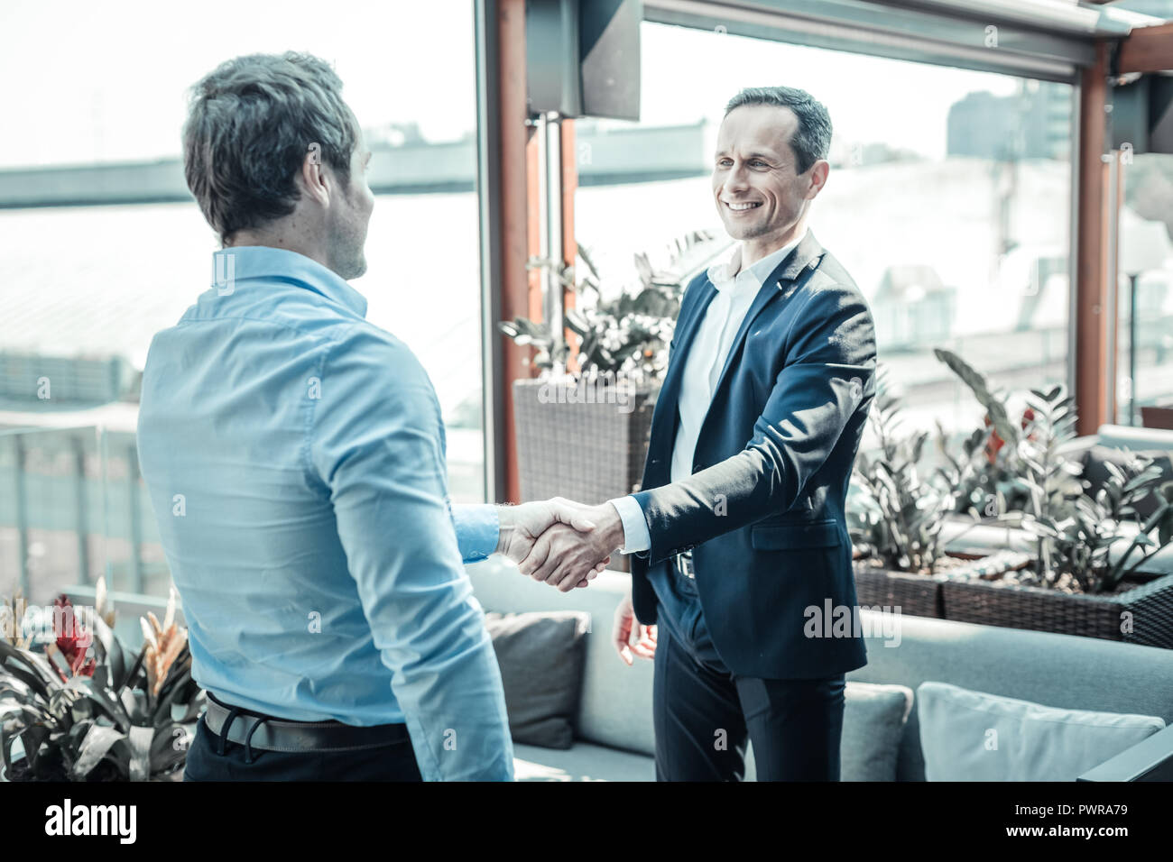 Positive delighted man welcoming his partner Stock Photo - Alamy