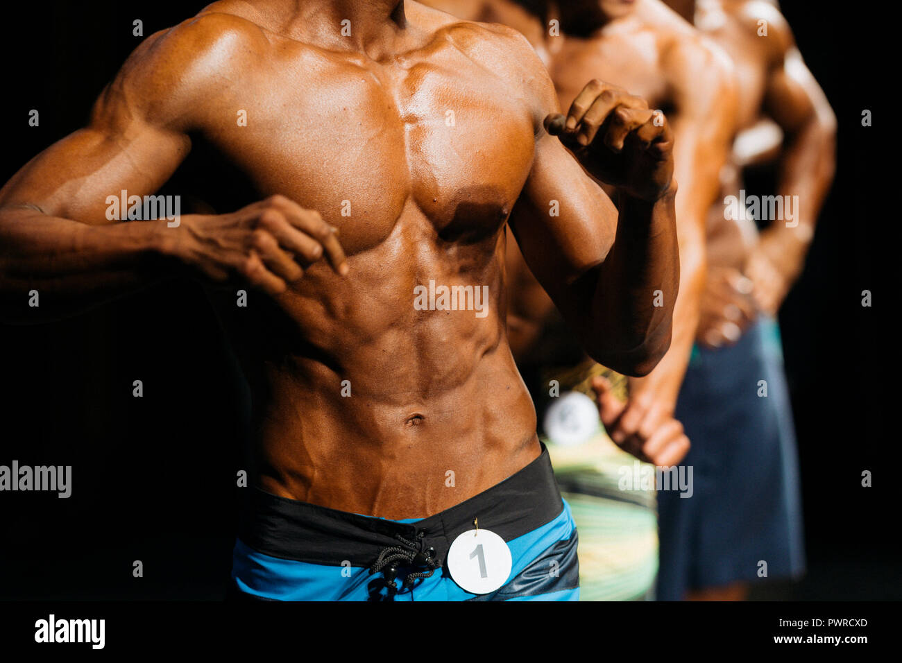athlete bodybuilder in colorful summer shorts at competitions in beach ...