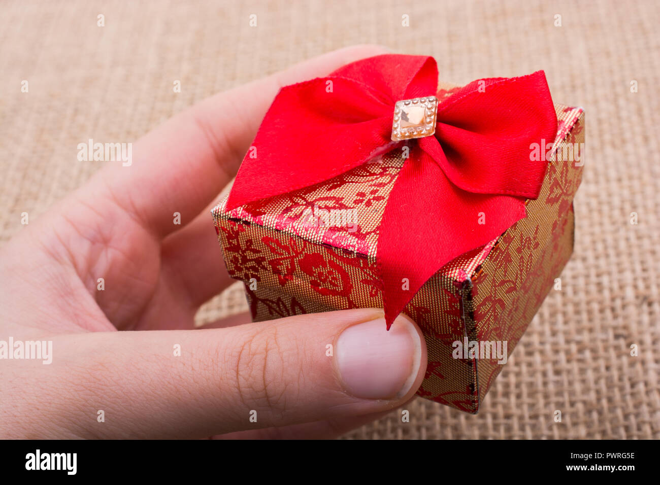 Gift box with red ribbon made of cardboard in hand Stock Photo - Alamy