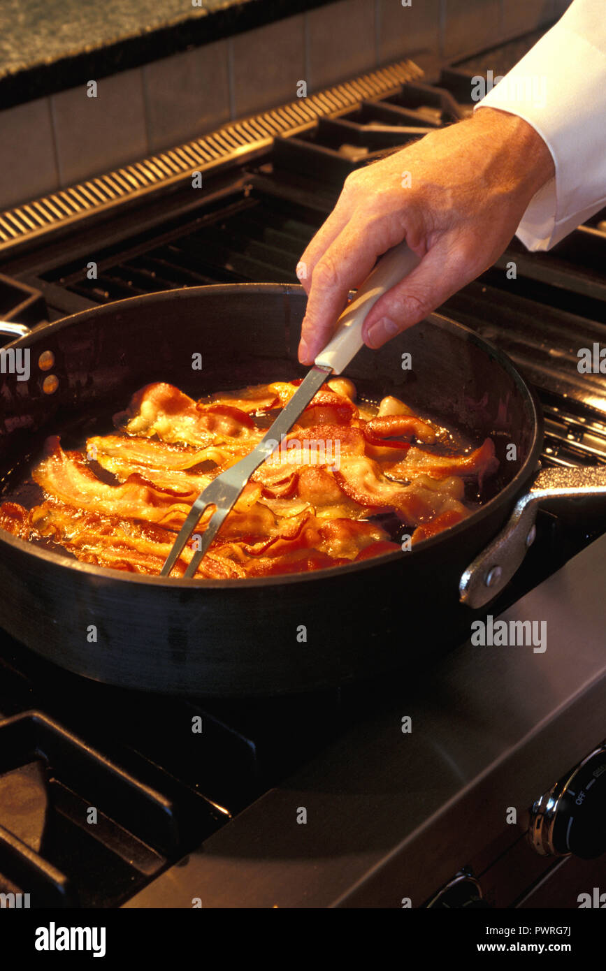 Chef frying bacon in a large skillet, USA Stock Photo - Alamy