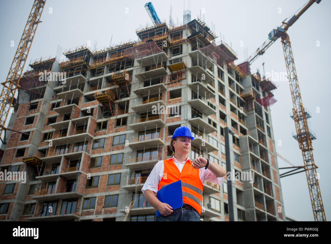 Engineer looking at his watch on a construction site in front of ...