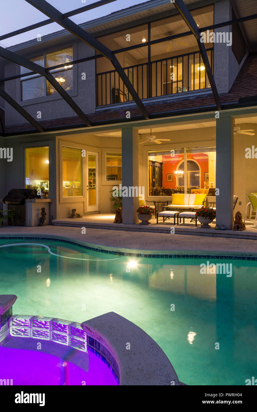 Nighttime view of luxury Florida home with screened in swimming pool ...