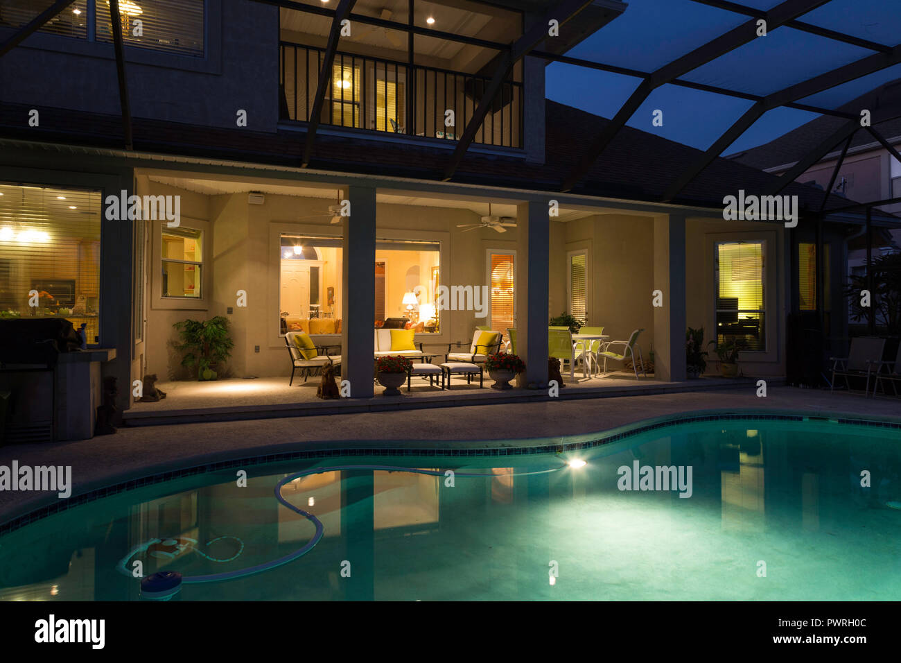 Nighttime view of luxury Florida home with screened in swimming pool ...
