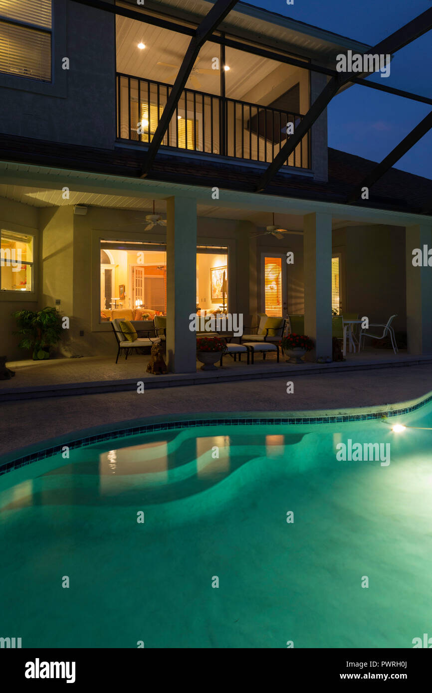Nighttime view of luxury Florida home with screened in swimming pool ...