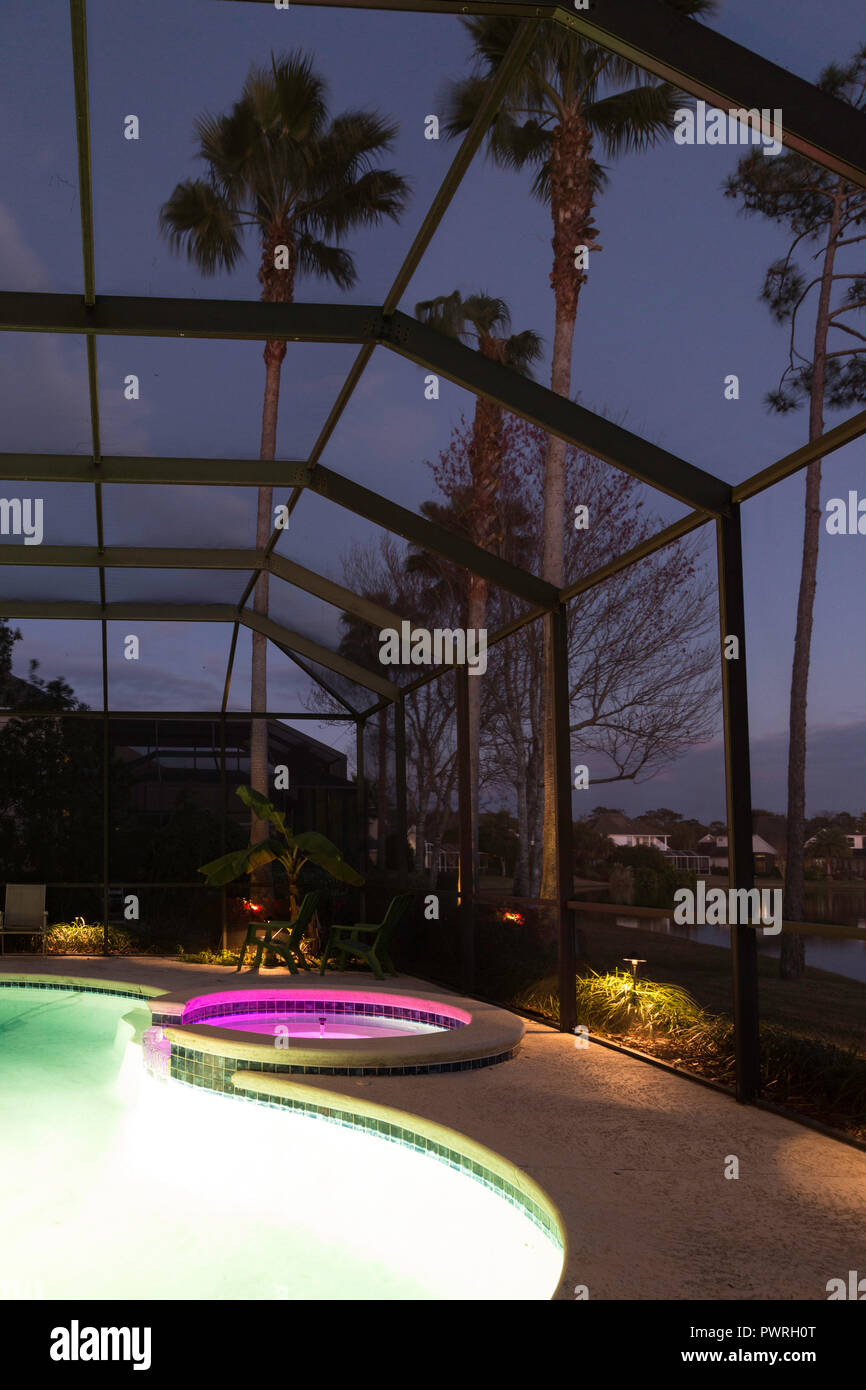 Nighttime view of luxury Florida home with screened in swimming pool ...