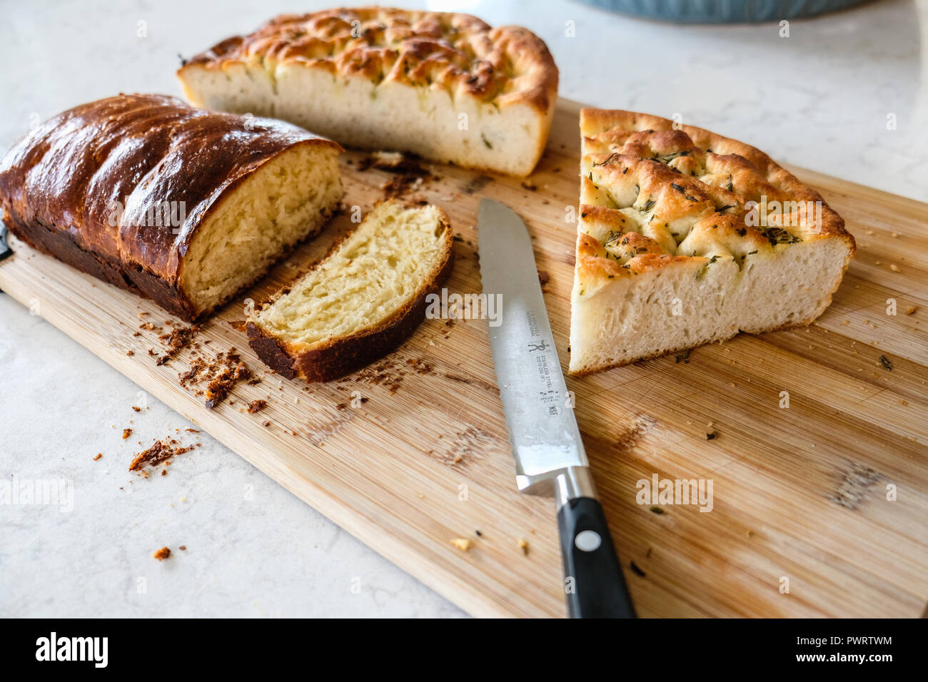 Close up of female hand cutting home made fresh breads on kitchen ...