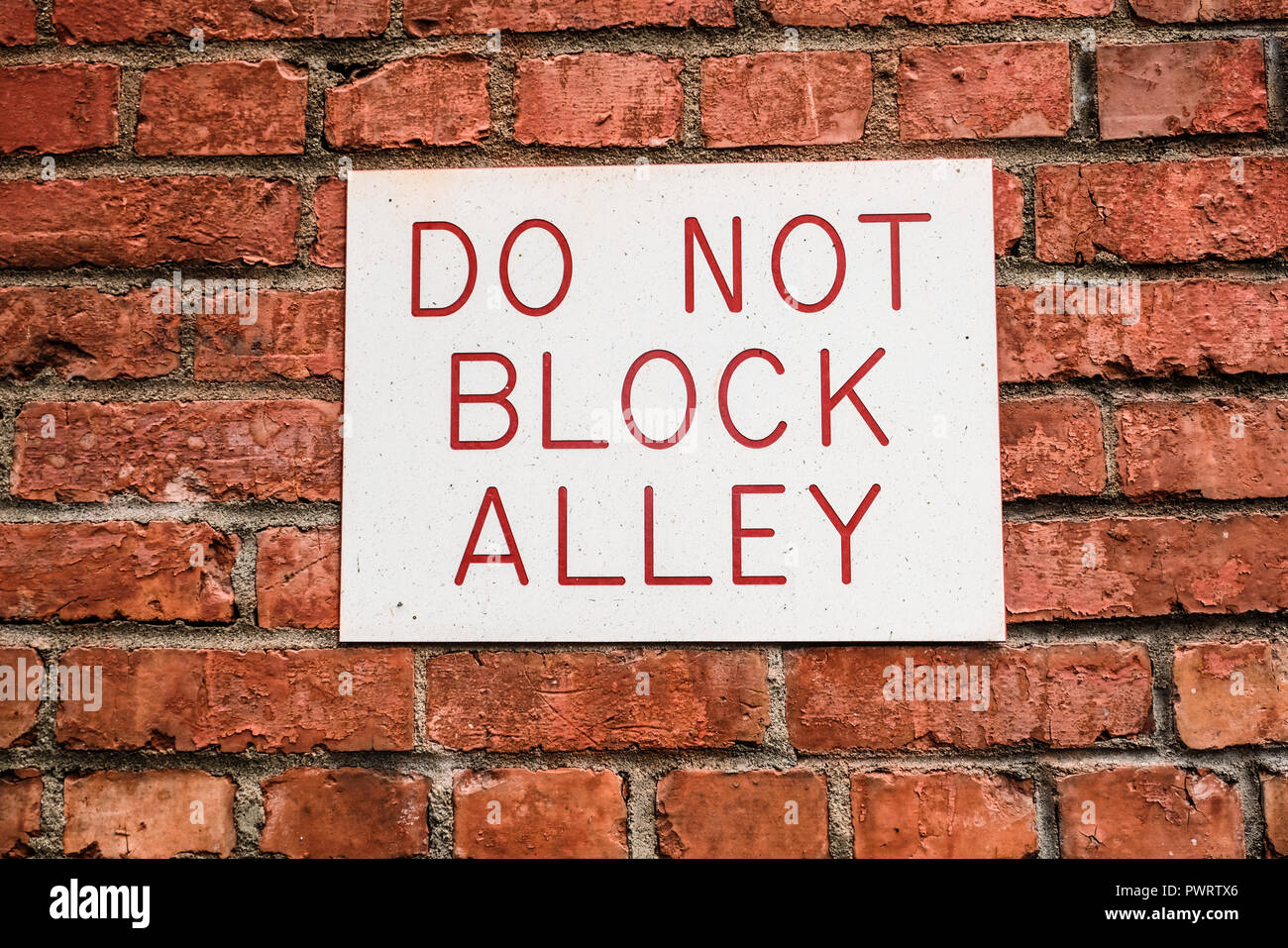 A Do Not Block Alley sign on a red brick wall Stock Photo - Alamy
