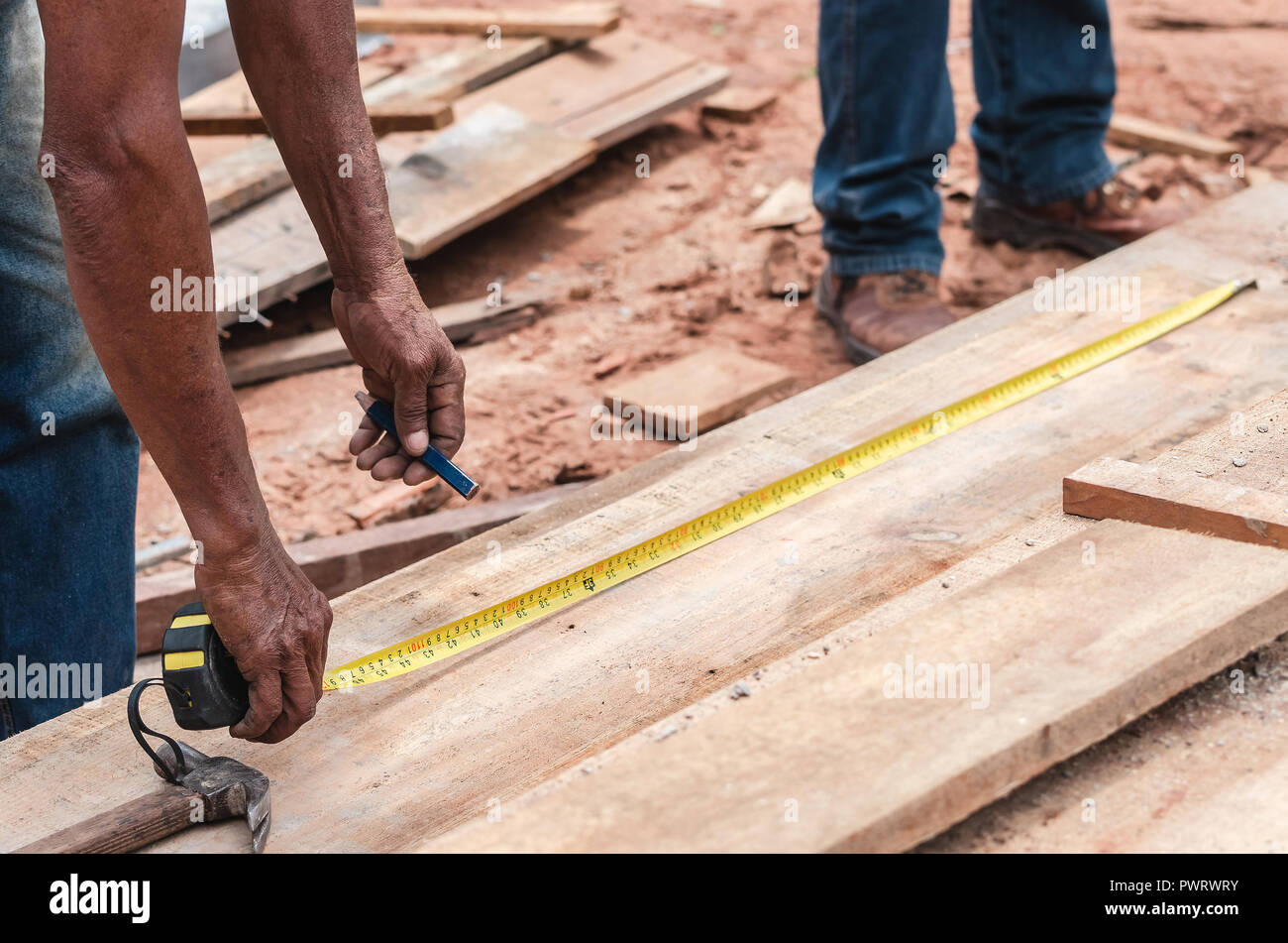 Hands of a carpenter with a measuring tape, measuring the size of a ...