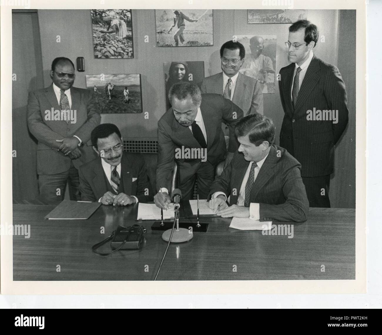 THE MAN IN THE BACK IS SIGNING SOME PAPERS WITH THE OTHER MEN SMILING ...