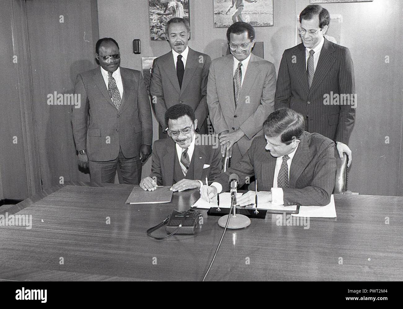 TWO MEN SIGNING PAPERS WITH FOUR OTHER MEN WATCHING Stock Photo - Alamy