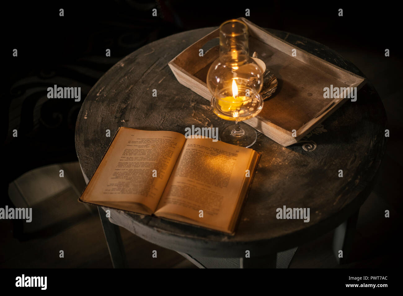 open book under the lamp with a candle on wooden table, vintage scene ...