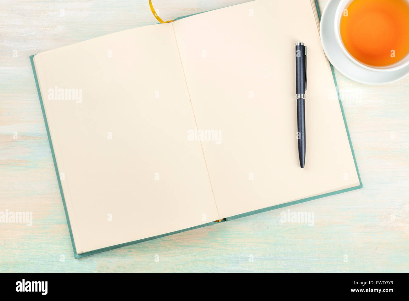 A photo of an open journal with a pen and a cup of tea, shot from the ...