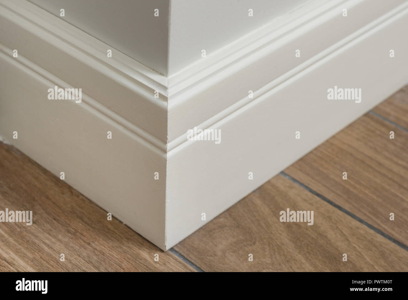 Molding in the interior, baseboard corner. Light matte wall with tiles ...