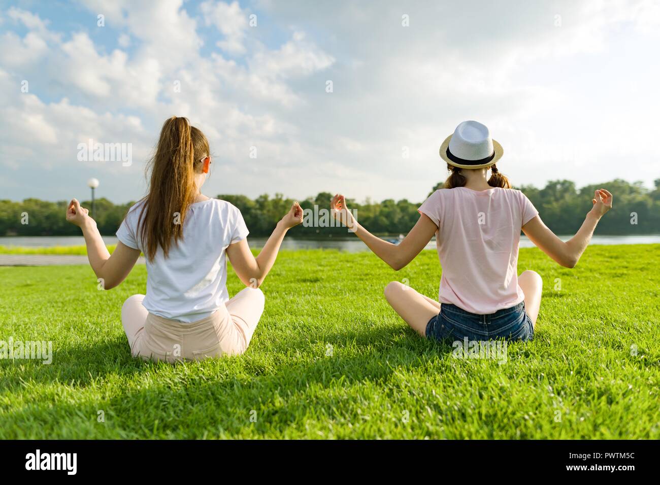 Two young girls doing yoga pose outdoor, yoga at sunset in the park ...