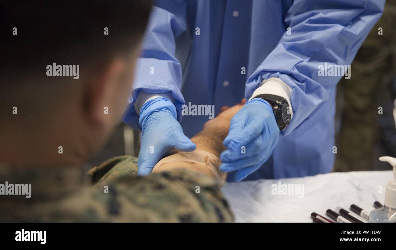 A Navy Corpsman bandages a Marine’s arm after drawing blood during a ...