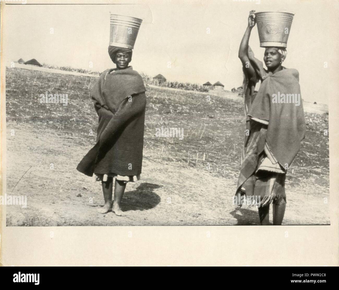 TWO WOMEN WALKING ON THE ROAD WITH A BUCKET ON THERE HEADS Stock Photo ...