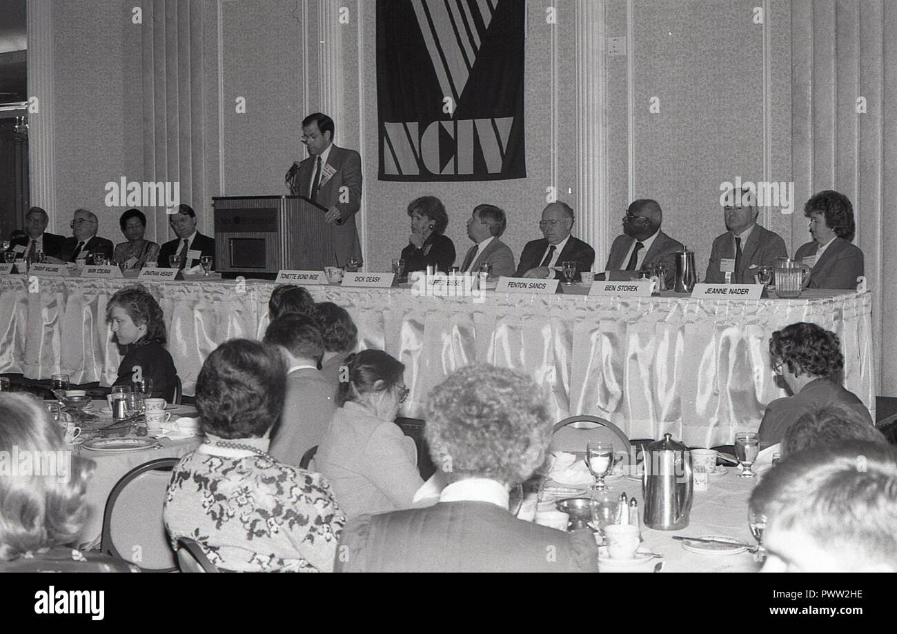 MARK IS AT THE PODIUM GIVING HIS SPEECH TO A GROUP OF MEN AND WOMEN AT ...