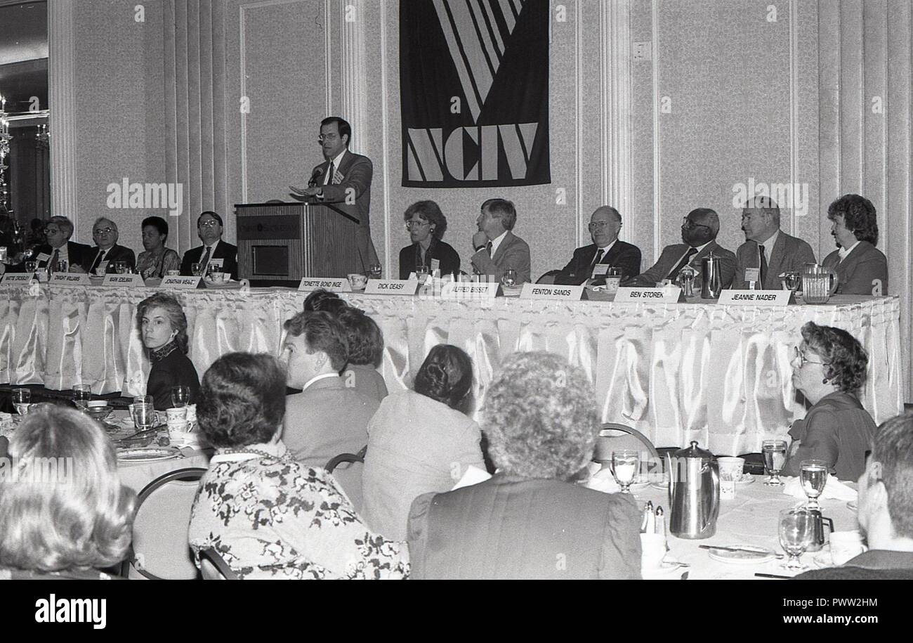 MARK IS AT THE PODIUM GIVING HIS SPEECH TO A GROUP OF MEN AND WOMEN AT ...