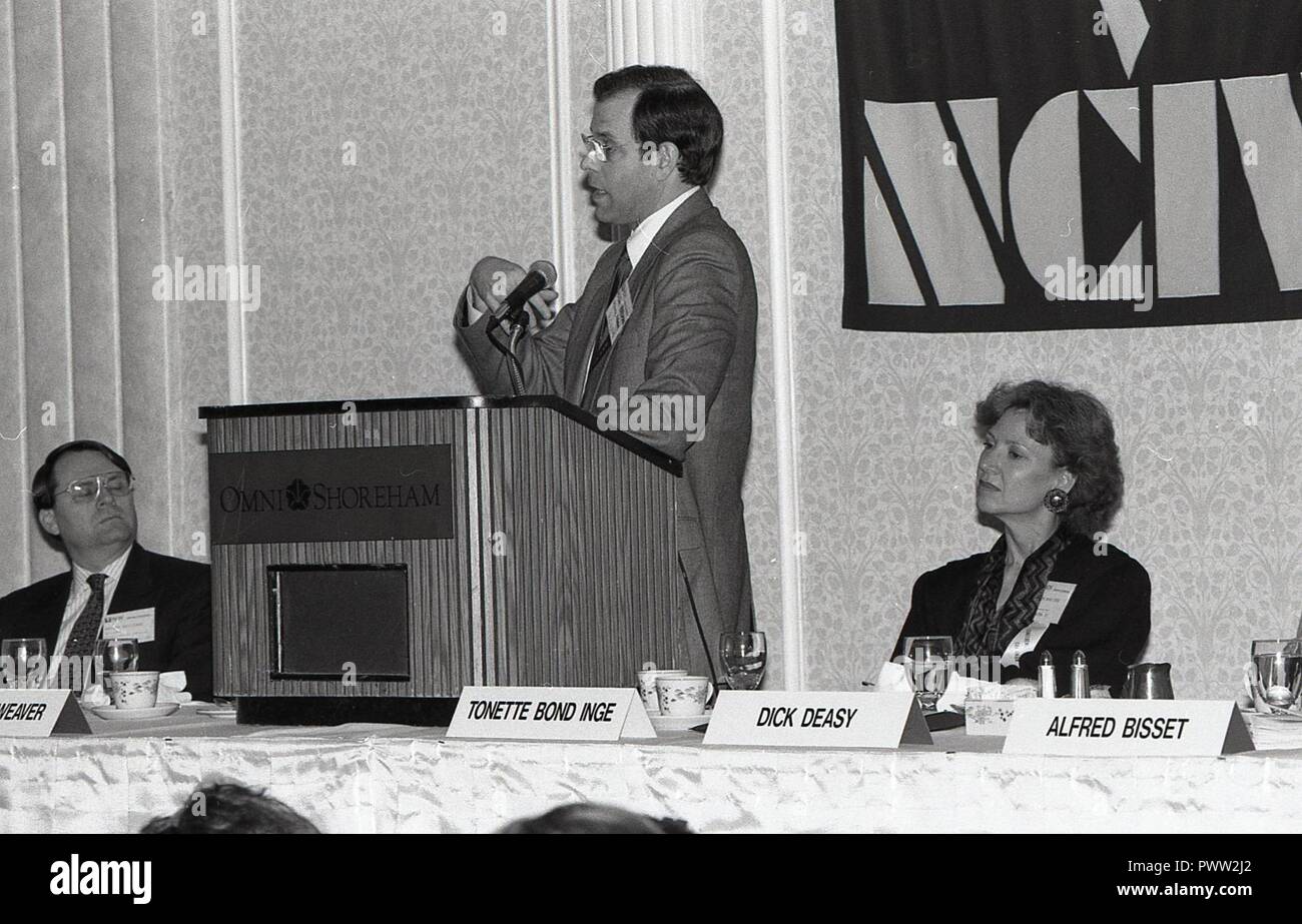 MARK IS AT THE PODIUM GIVING HIS SPEECH TO A GROUP OF MEN AND WOMEN AT ...