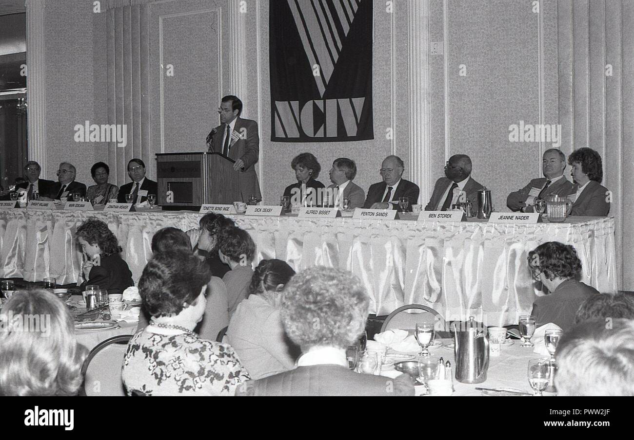 MARK IS AT THE PODIUM GIVING HIS SPEECH TO A GROUP OF MEN AND WOMEN AT ...