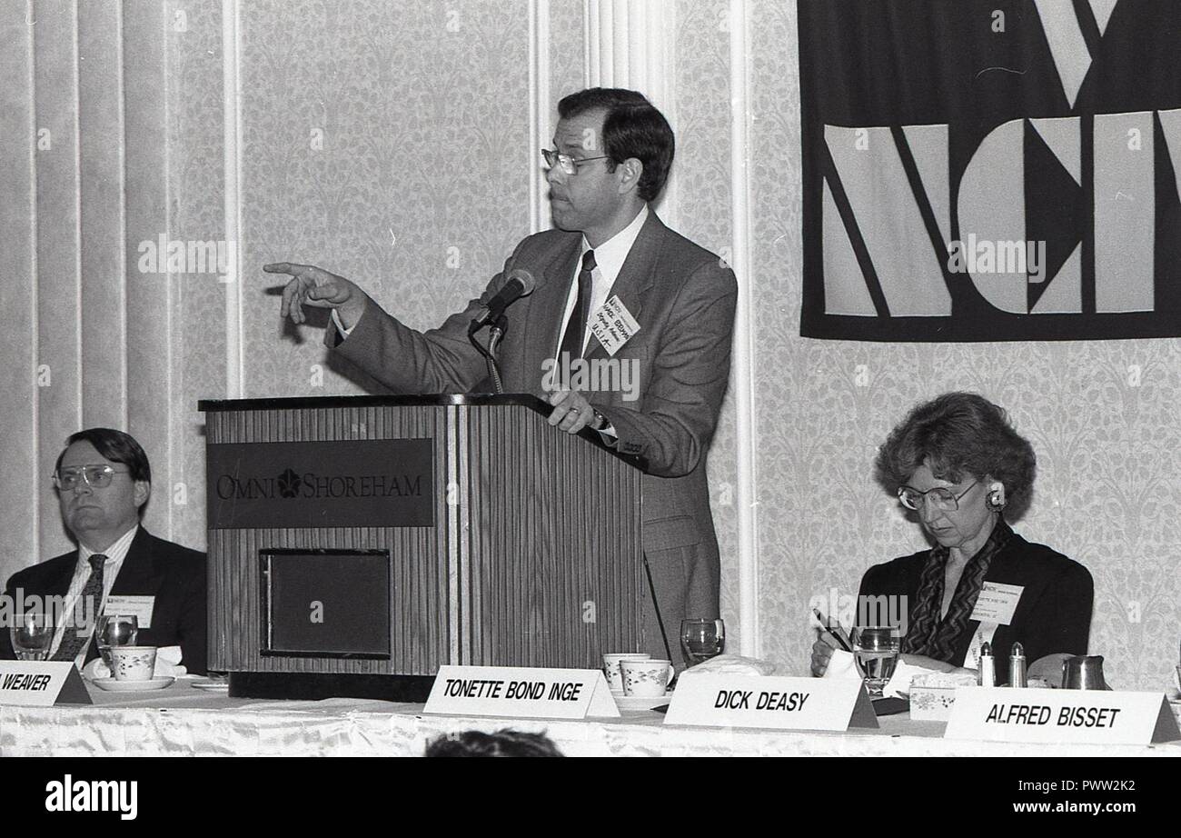 MARK IS AT THE PODIUM GIVING HIS SPEECH TO A GROUP OF MEN AND WOMEN AT ...