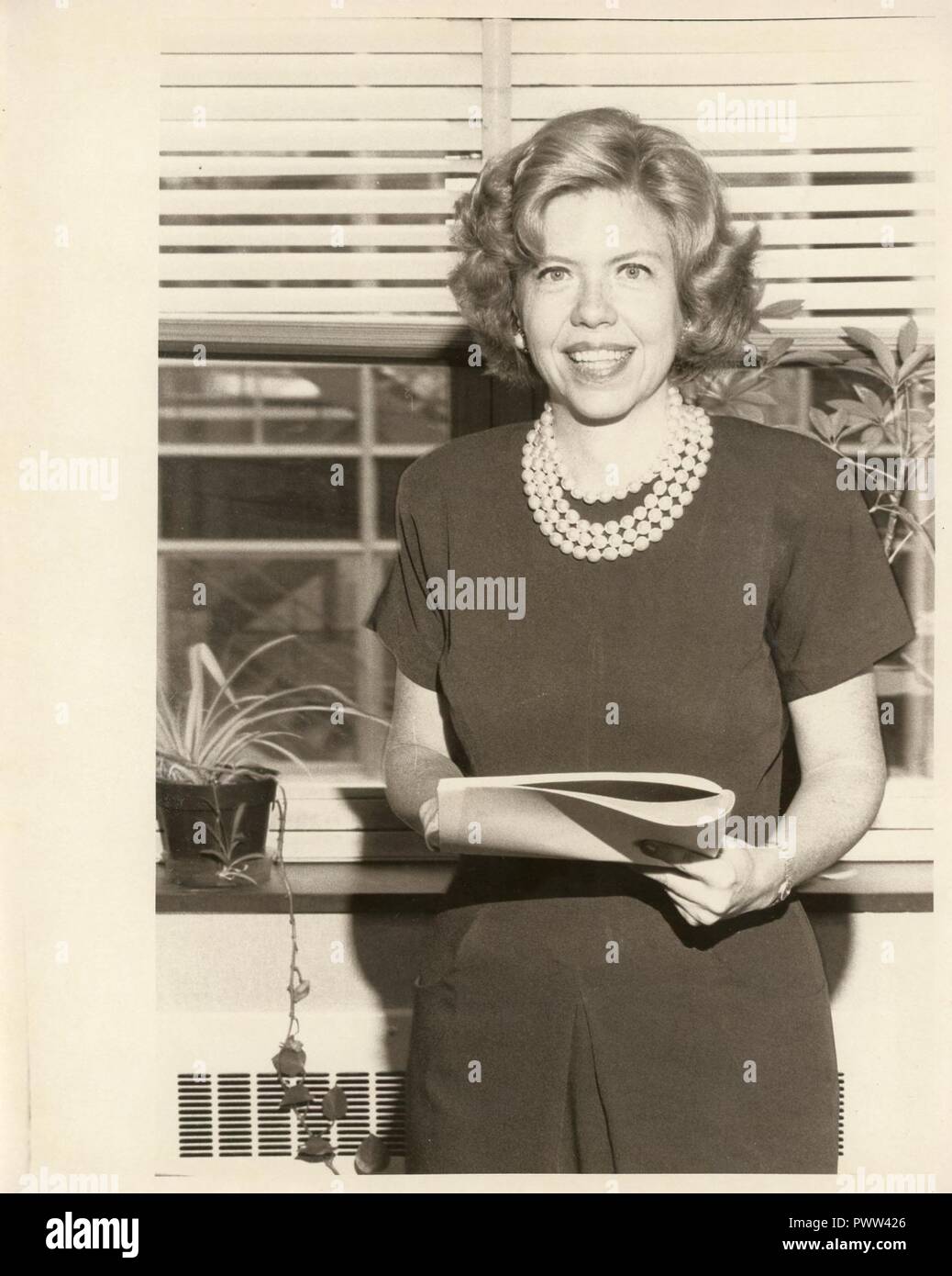 BARBARA UPTON IS STANDING AND SMILING WITH SOME PAPERS IN HER HANDS ...