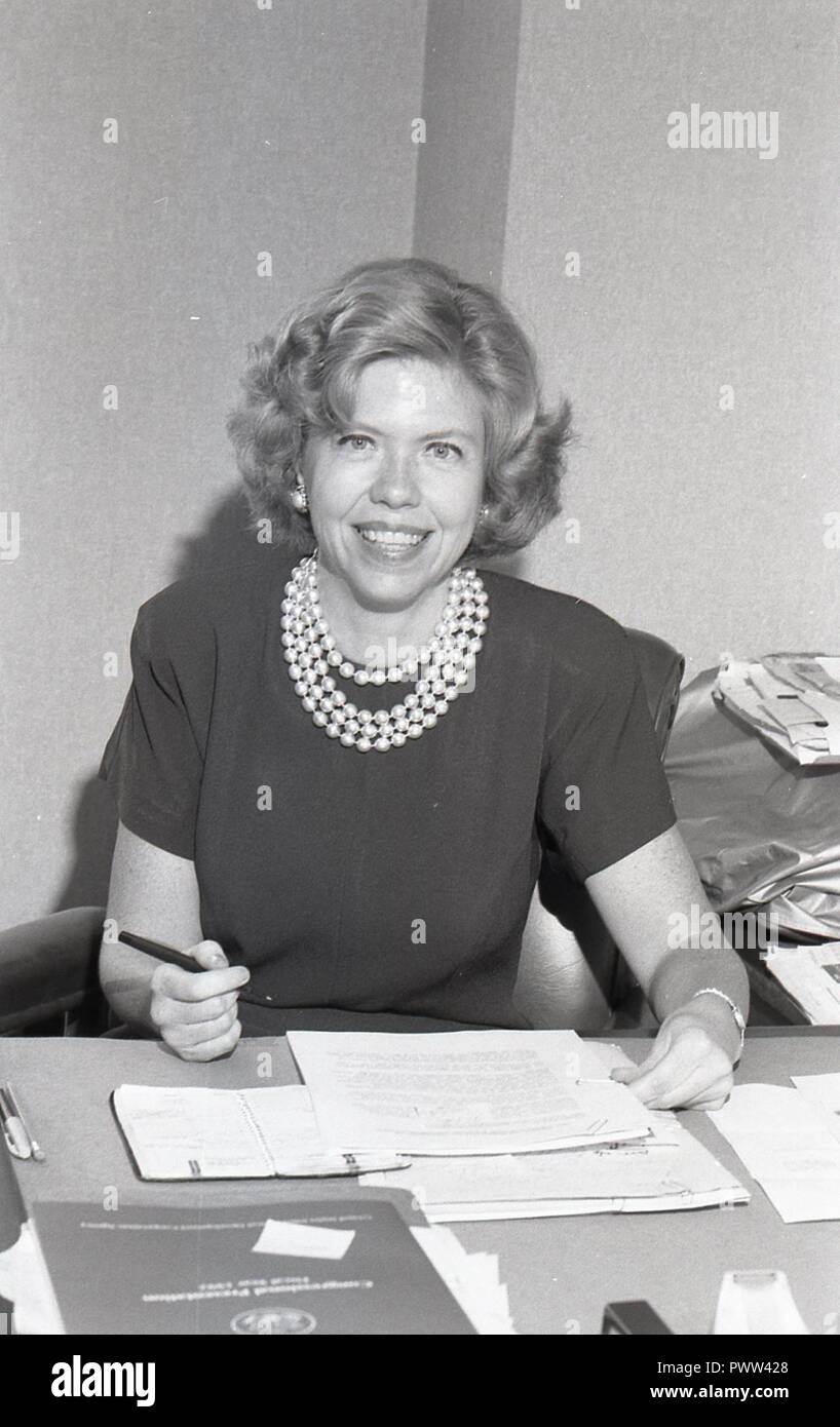 BARBARA UPTON IS SMILING SITTING AT HER DESK WITH SOME PAPER WORK IN ...