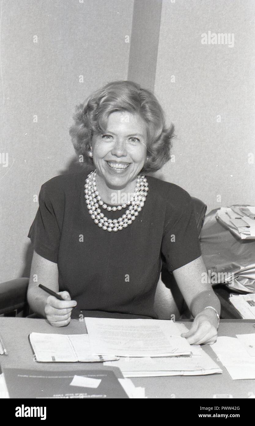BARBARA UPTON IS SMILING SITTING AT HER DESK WITH SOME PAPER WORK IN ...