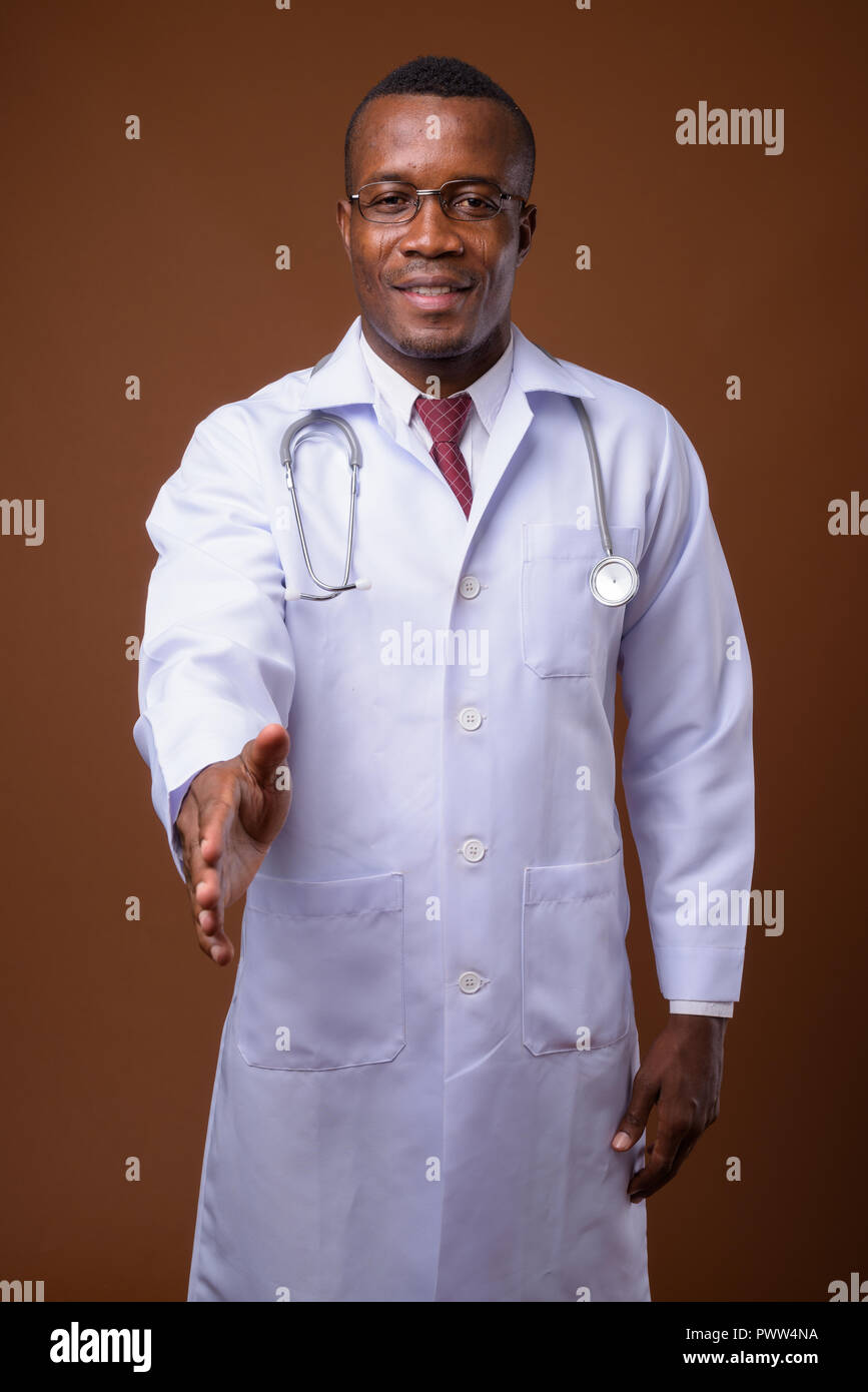 Studio shot of young African man doctor against brown background Stock ...