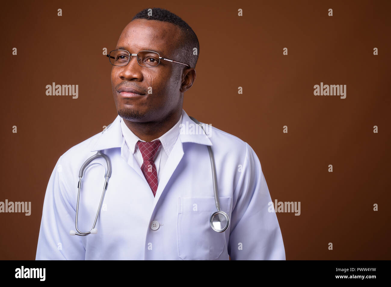 Studio shot of young African man doctor against brown background Stock ...