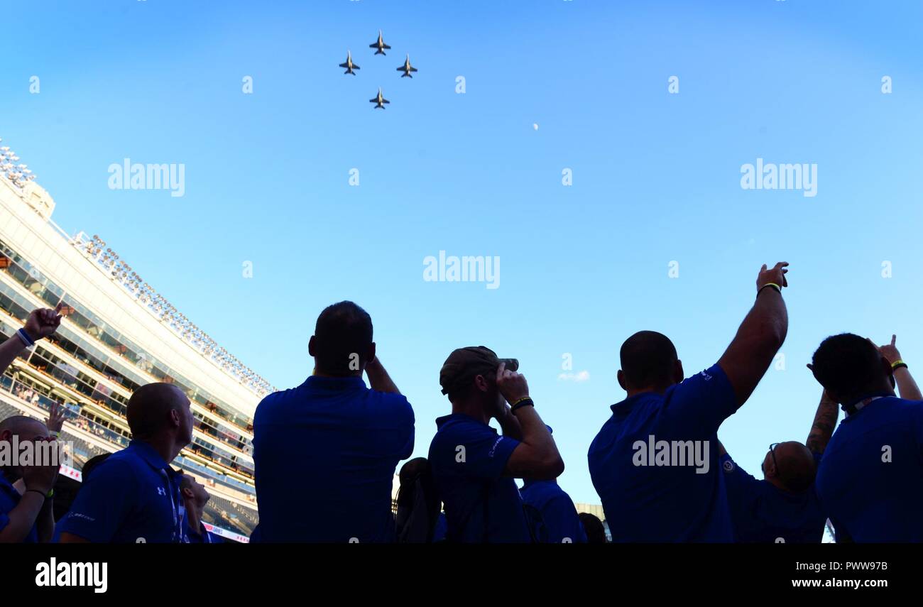 Members of Team Air Force cheer while watching a four-ship flyover ...