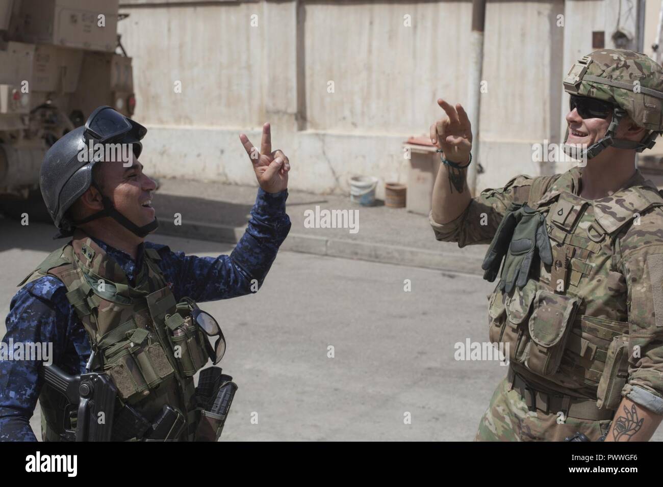 An Iraqi Federal Police member makes a peace sign with a U.S. Army ...