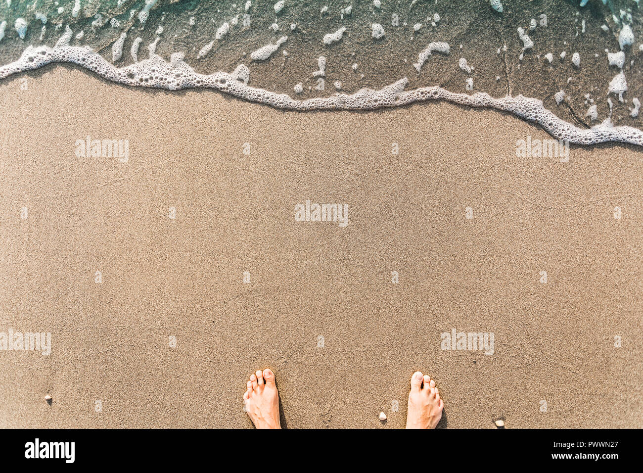 Blue waves in the sand with male feet Stock Photo - Alamy