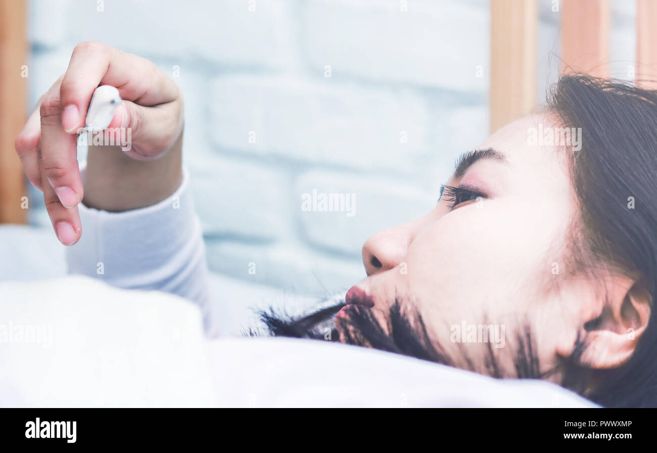 Asian woman use a thermometer to detect fever in bedroom.color tone ...