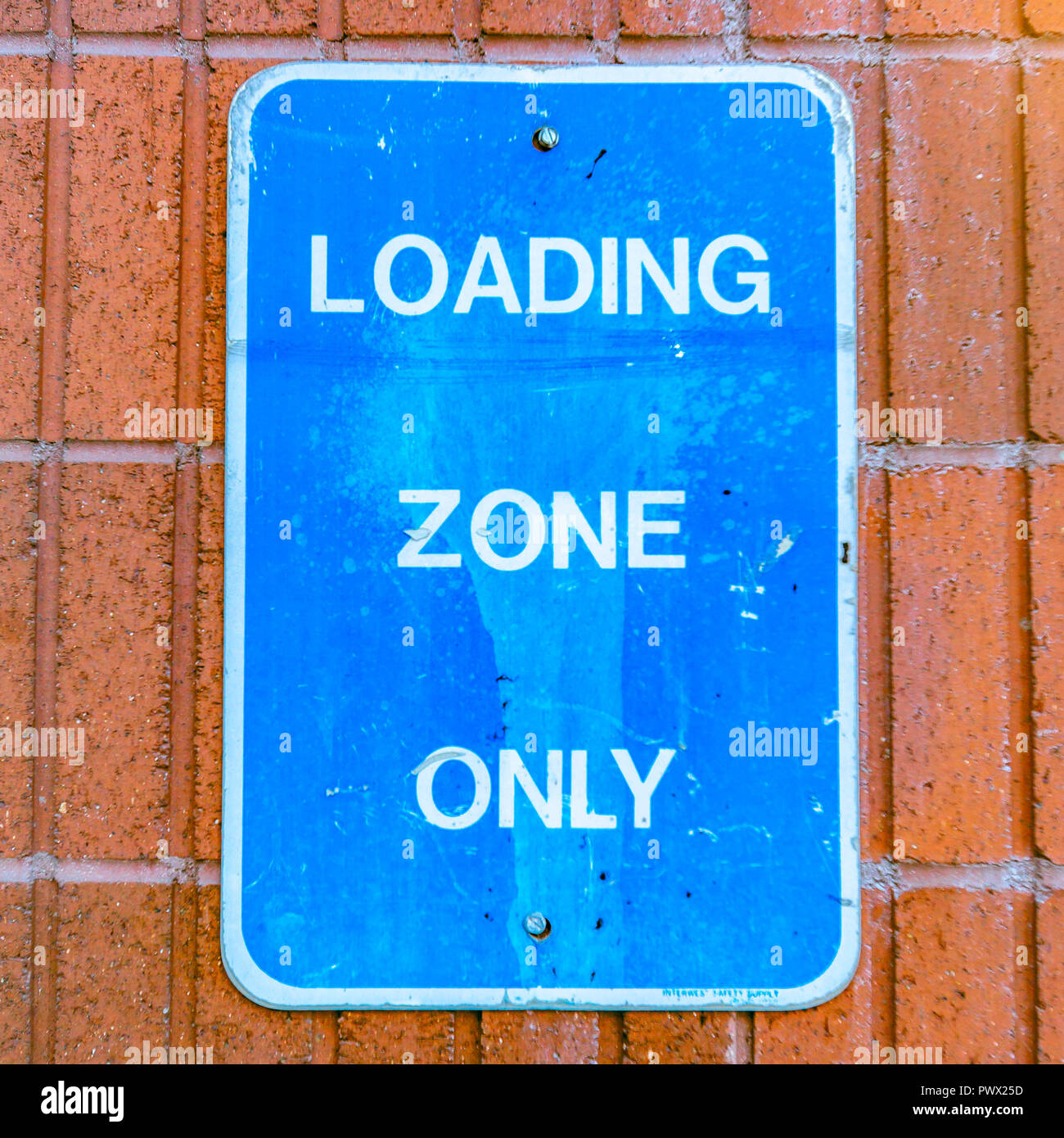 Loading Zone Only Sign nailed to a red brick wall Stock Photo - Alamy