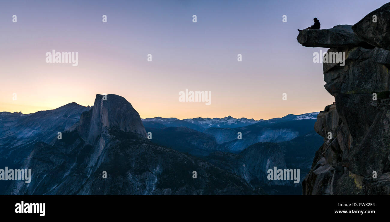 Man on a cliff with view of rock mountain below Stock Photo - Alamy