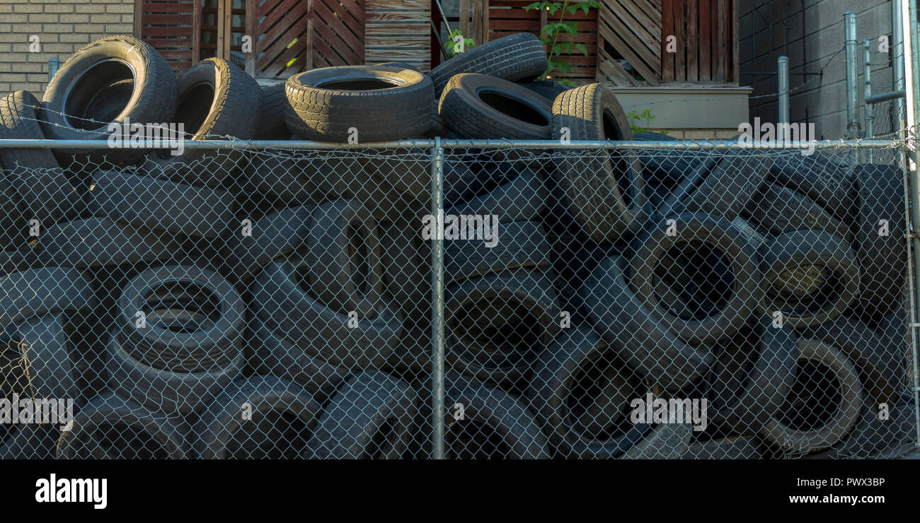 Old tires inside a mesh fence with barbed wire Stock Photo - Alamy