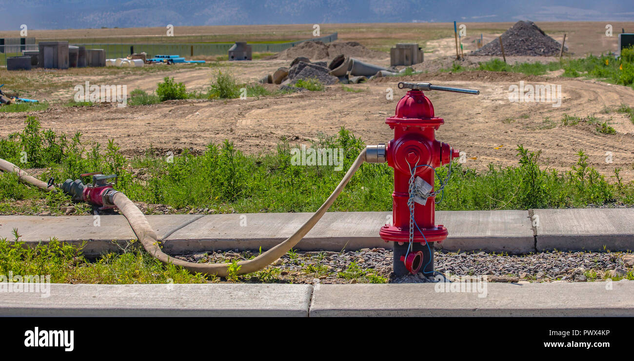 Red fire hydrant with connected hose and wrench Stock Photo - Alamy