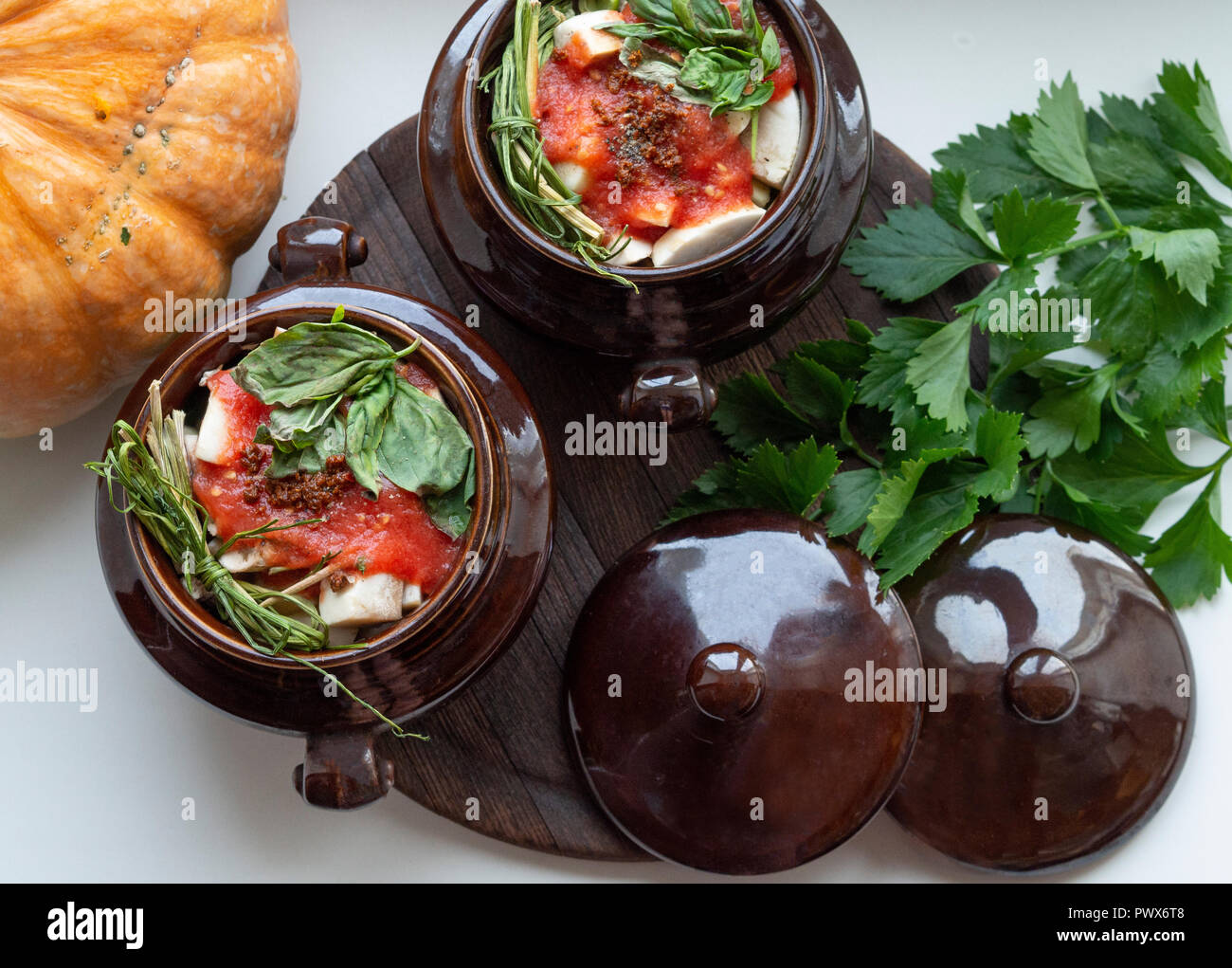 Top view image of two clay pots with vegetables, greenery and seasoning ...