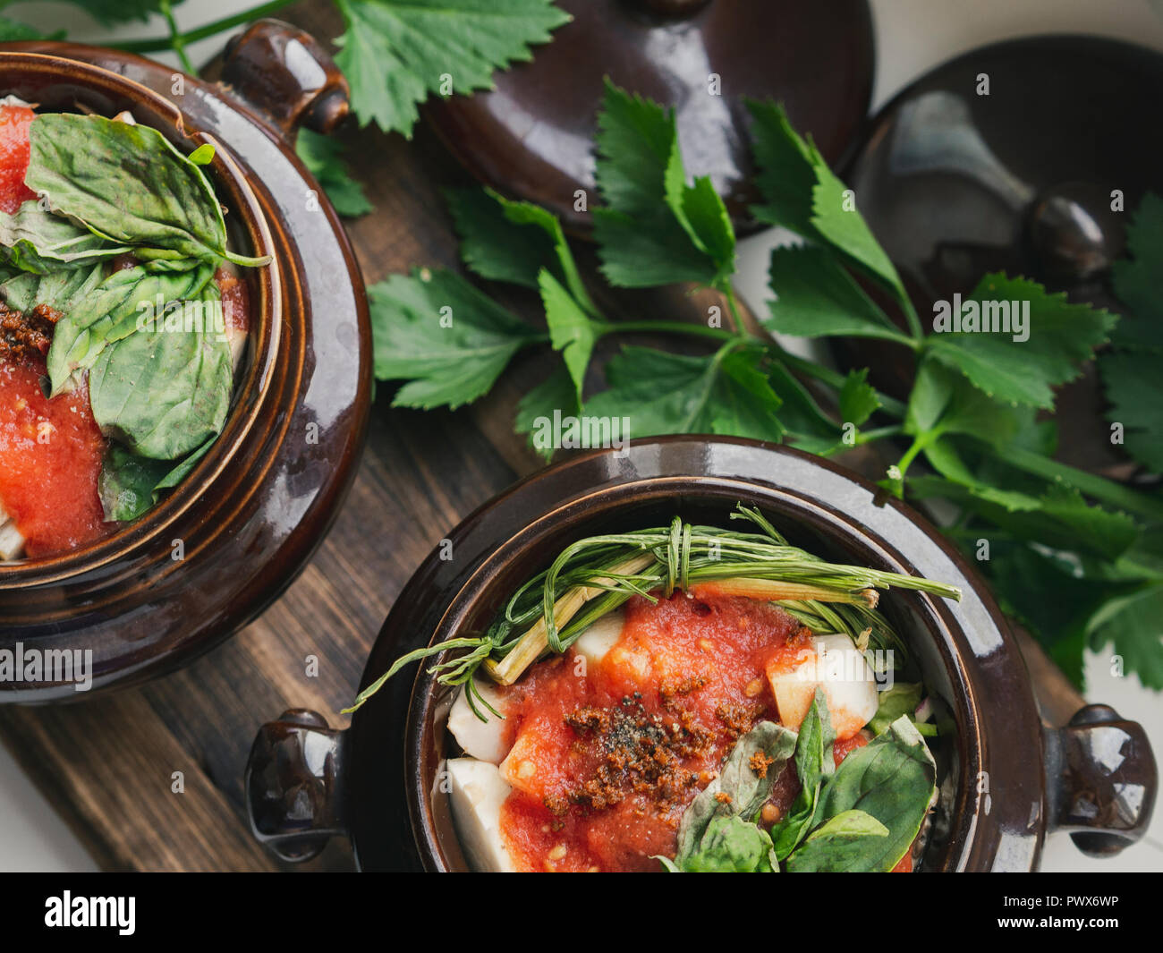 Top view image of two clay pots with vegetables, greenery and seasoning ...
