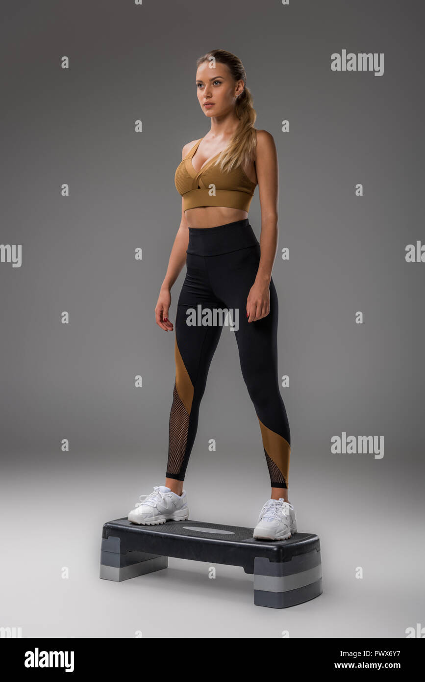 attractive young woman doing step aerobics on grey Stock Photo - Alamy