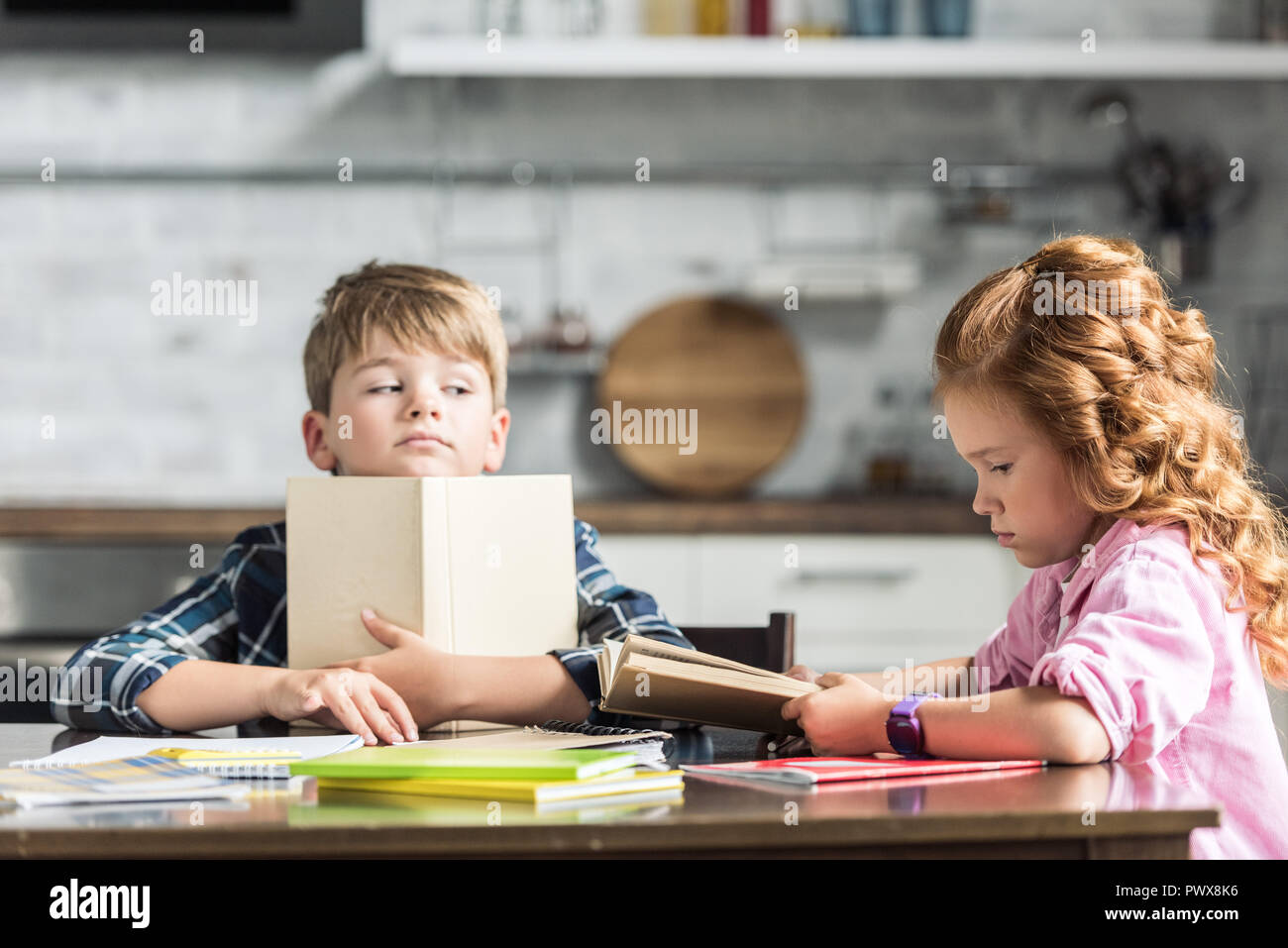 little brother and sister doing homework together at kitchen Stock ...