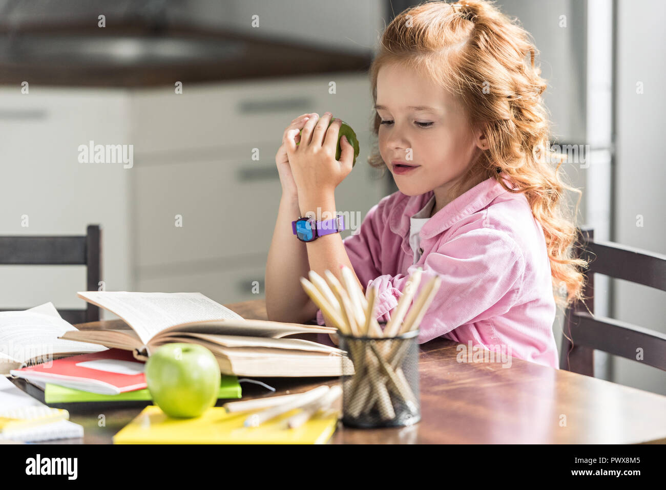 cute little schoolgirl with green apple doing homework Stock Photo - Alamy