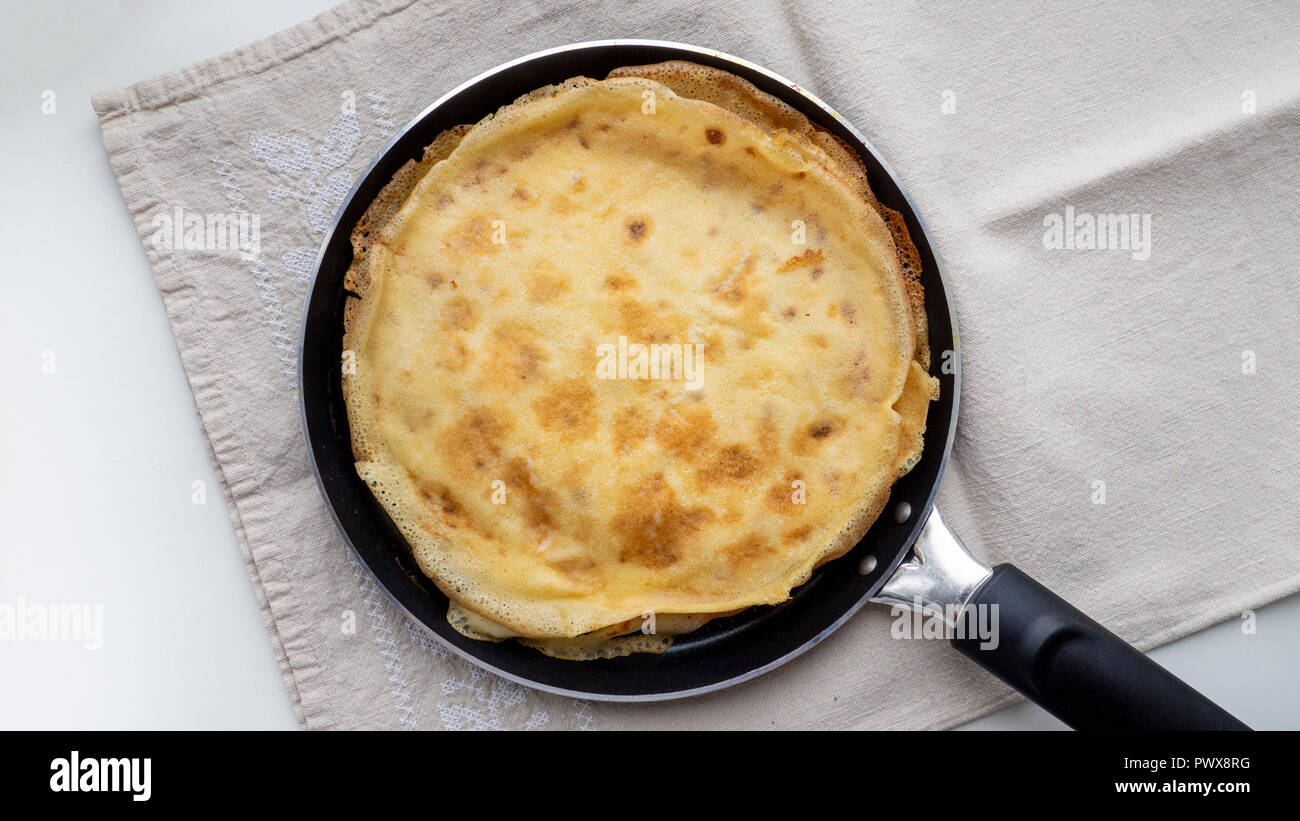 Stack of national slavic thin golden pancakes on the pan with rustic ...