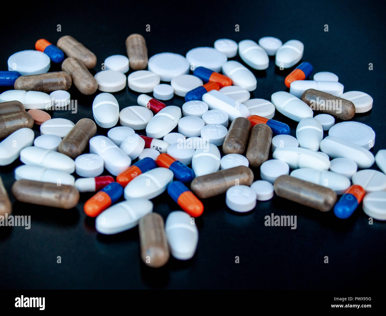 Pills of different sizes, shapes and colors with black background ...